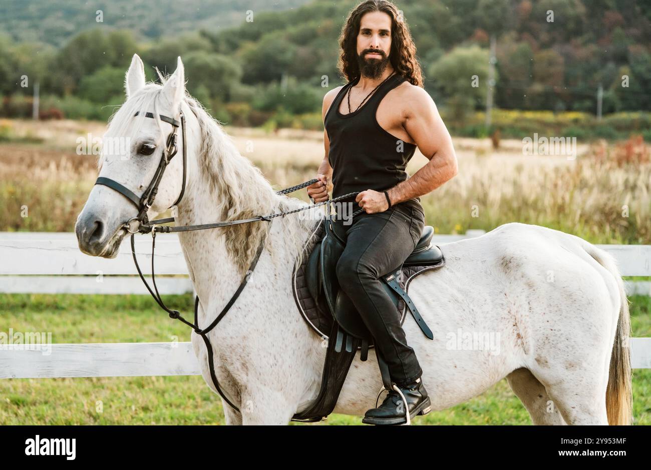 Young jockey training his horse for a ride. Good looking, hunky cowboy ...