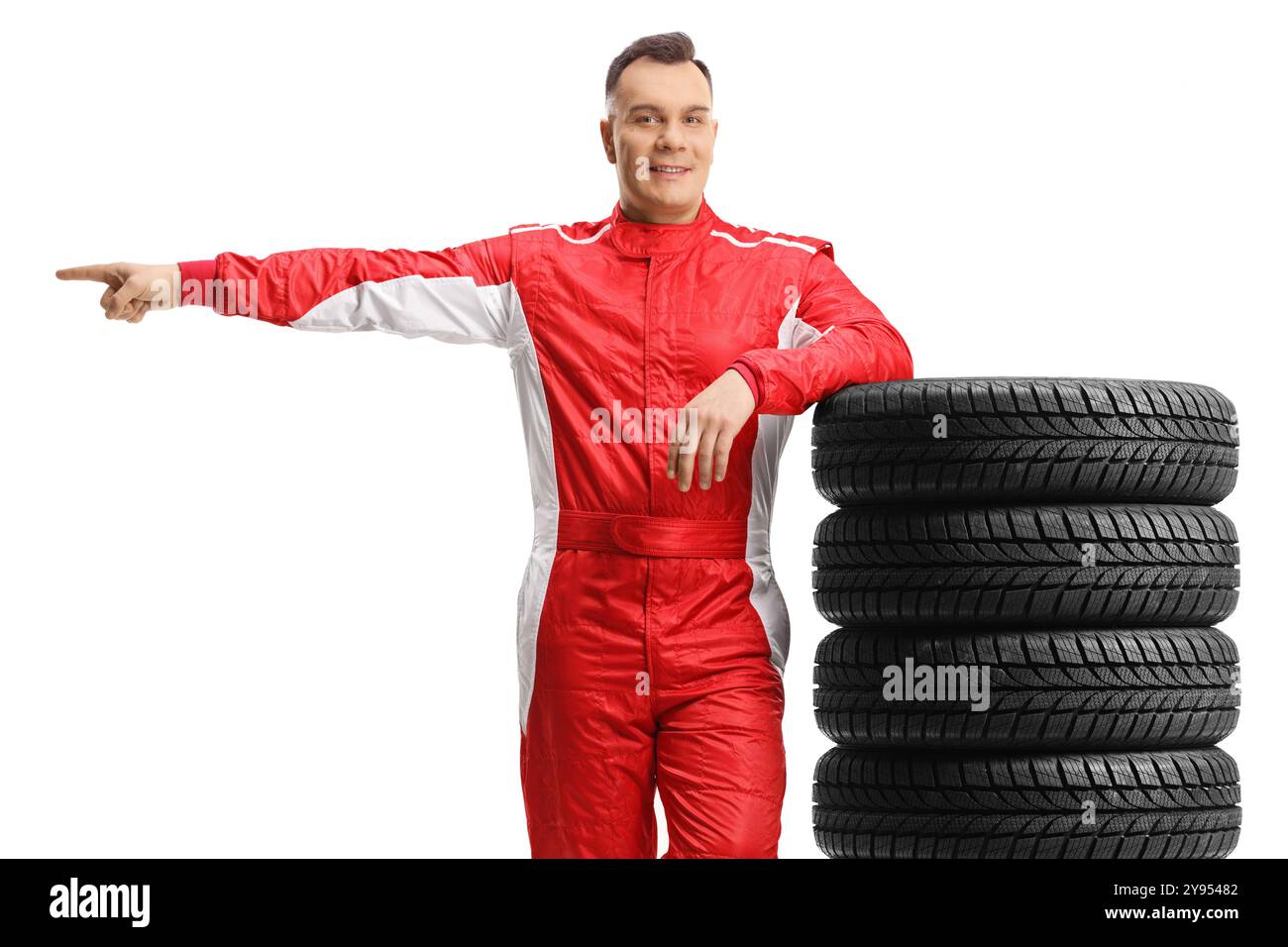 Car racer leaning on a pile of tires and pointing to the side isolated ...