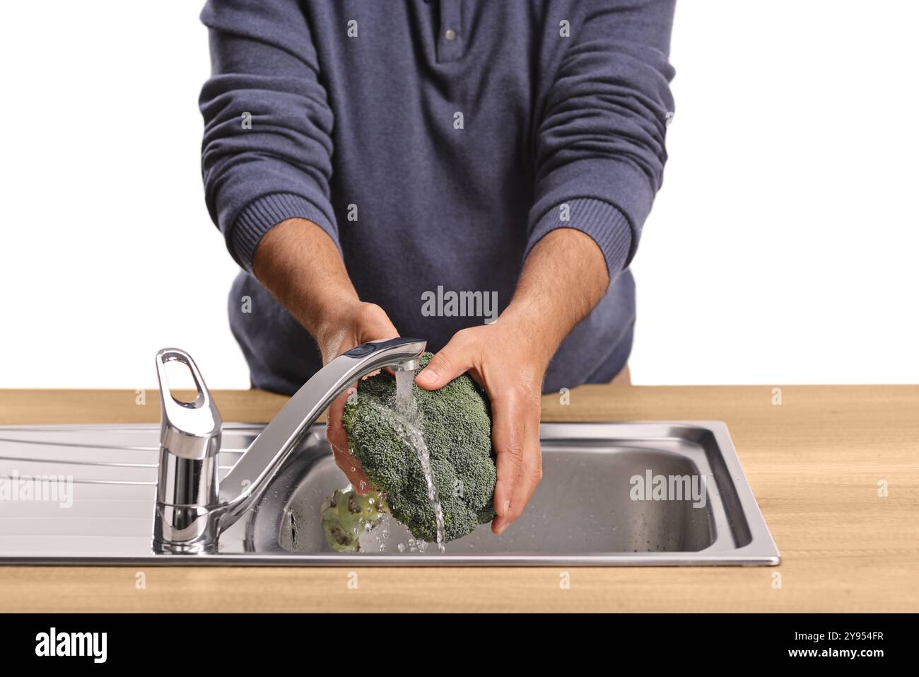 Man washing broccoli in a kitchen sink isolated on white background ...