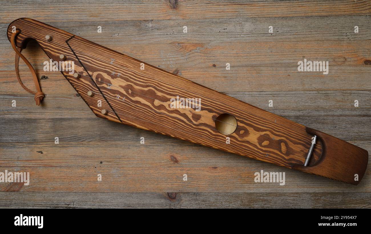 This image showcases a traditional wooden string instrument kantele ...
