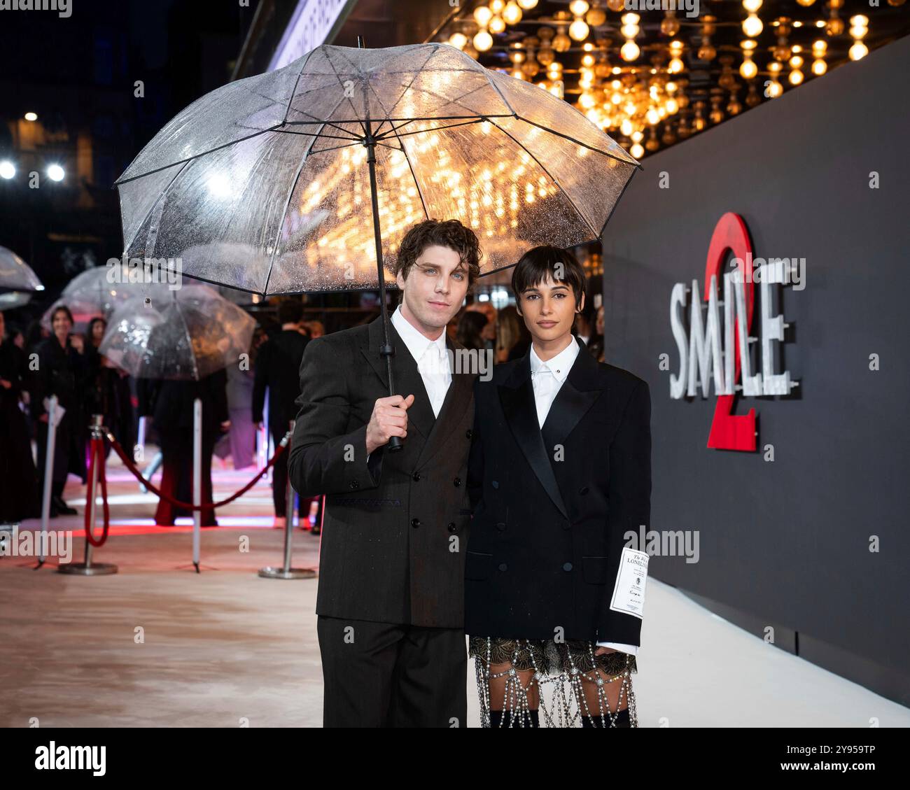 Lukas Gage, left, and Naomi Scott pose for photographers upon arrival ...