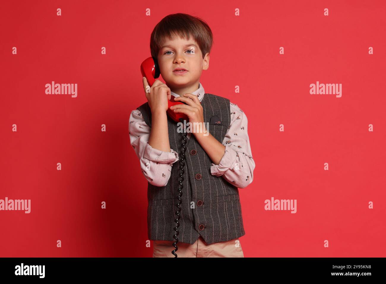 Cute little boy with handset of telephone on red background Stock Photo ...