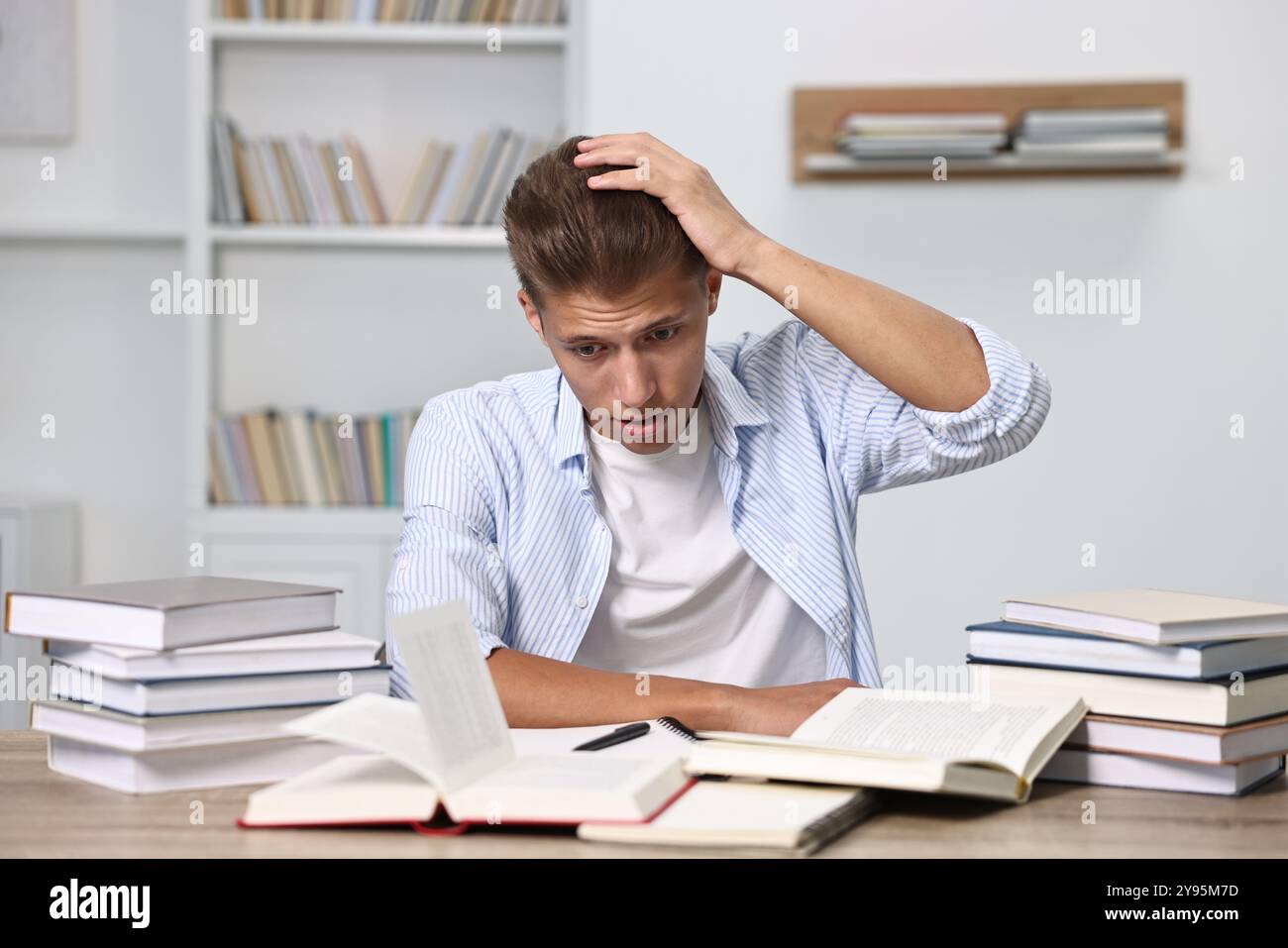 Overwhelmed student before exam at table among books indoors Stock ...