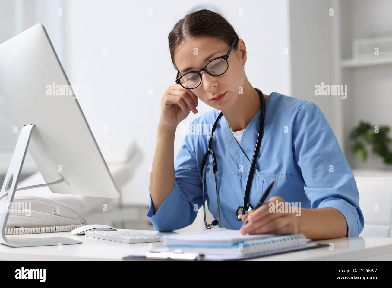 Nurse taking notes at white table in clinic Stock Photo - Alamy