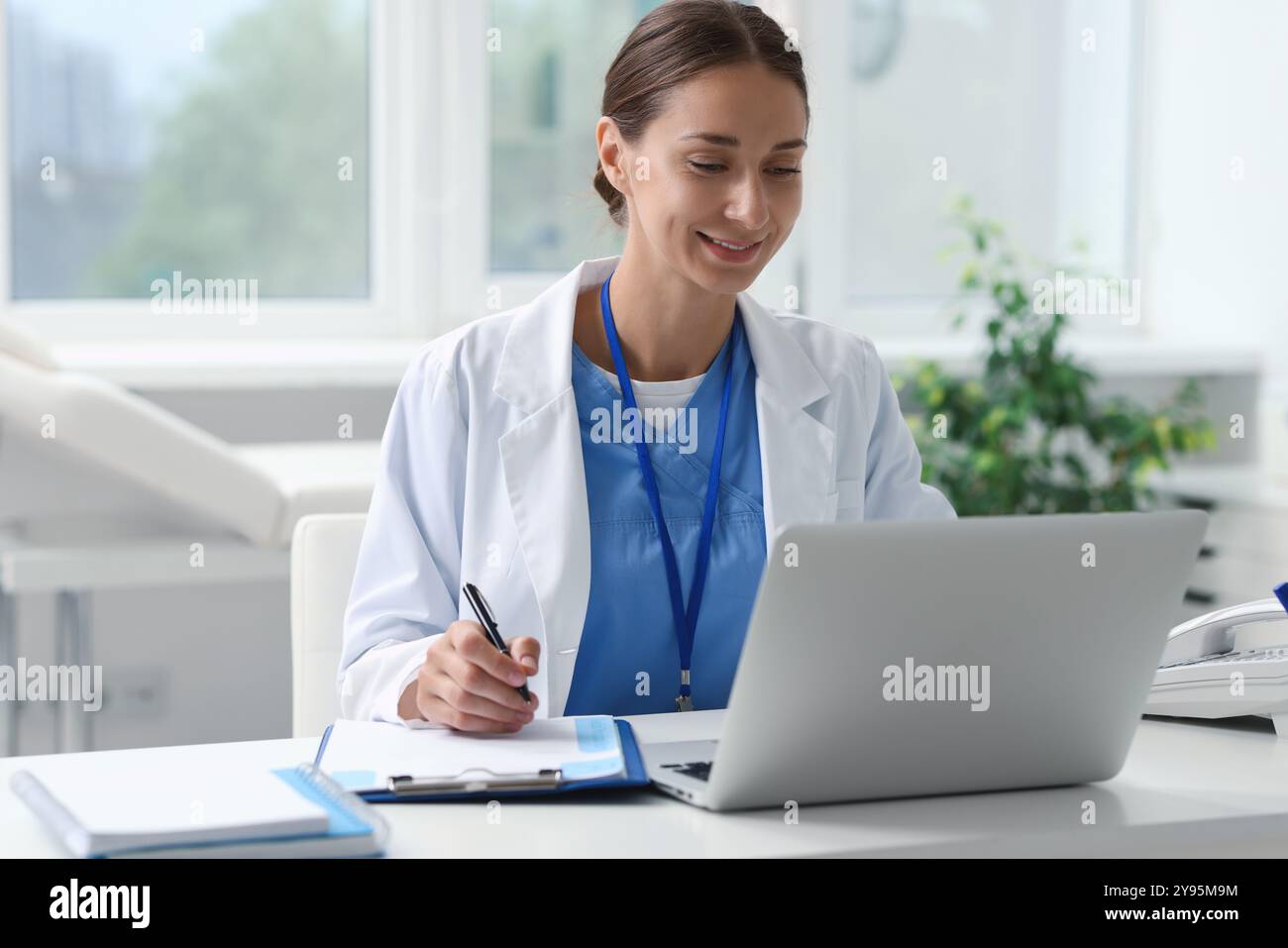 Nurse taking notes at white table in clinic Stock Photo - Alamy