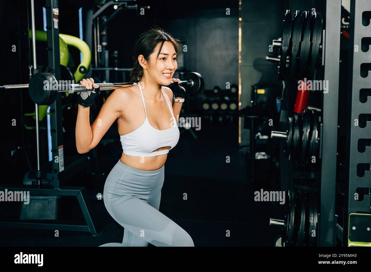 Asian woman muscular guy squat exercise with a lifting barbell in gym ...