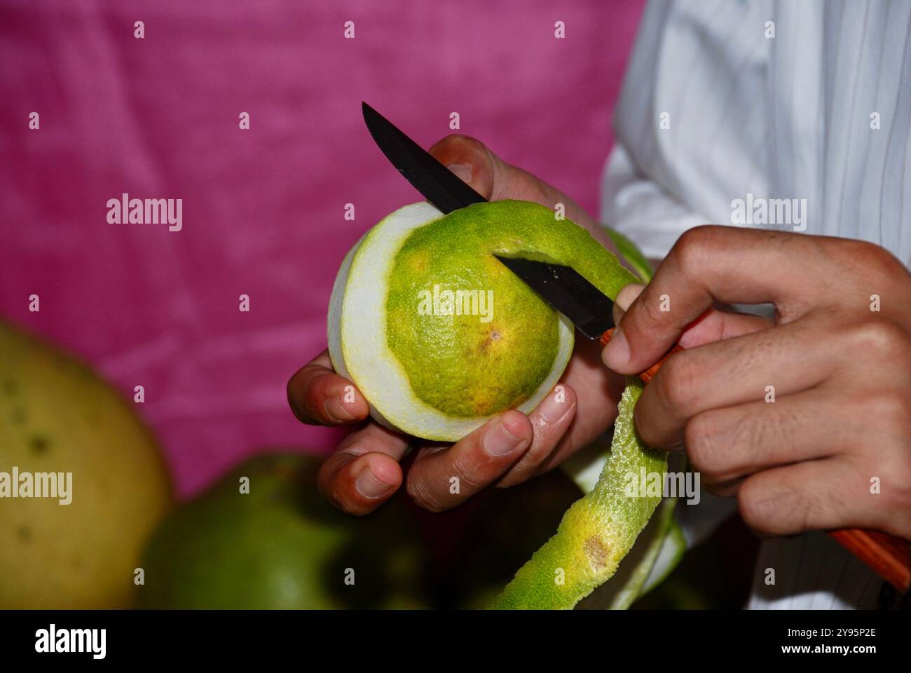 Man peeling orange skin using a knife, preparing slicing fruits for ...