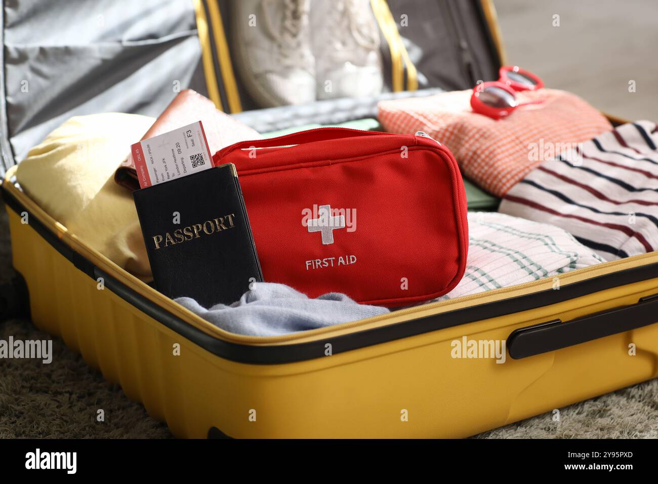Suitcase with first aid kit, stylish clothes and passport in room Stock ...