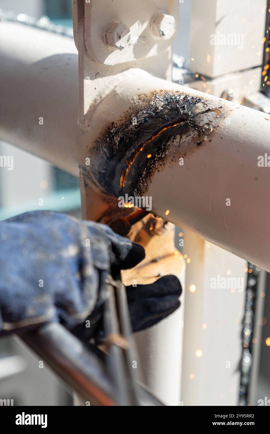 Construction worker is welding metal pipes on a building site, creating ...
