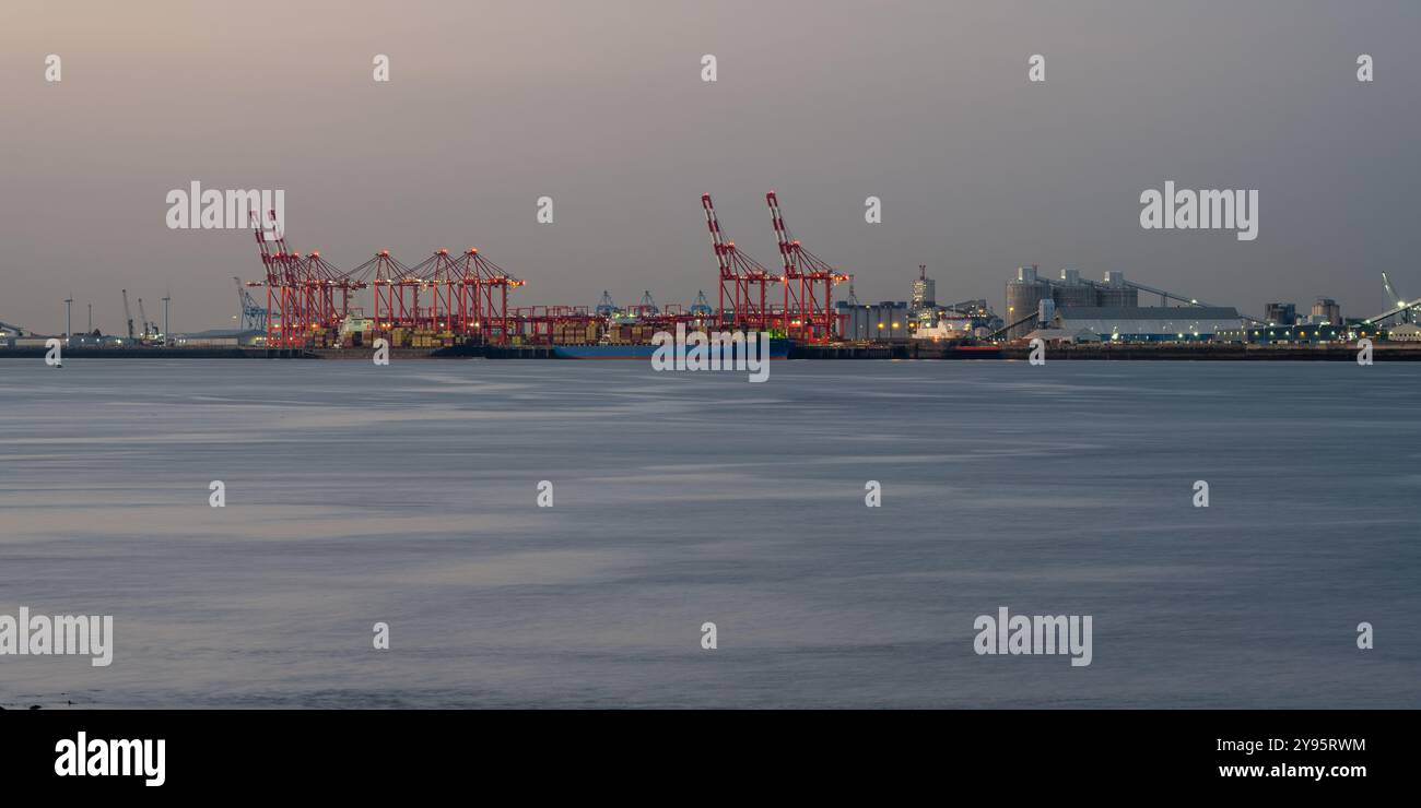 Cranes and container ships are lit at dusk at Liverpool Docks in ...