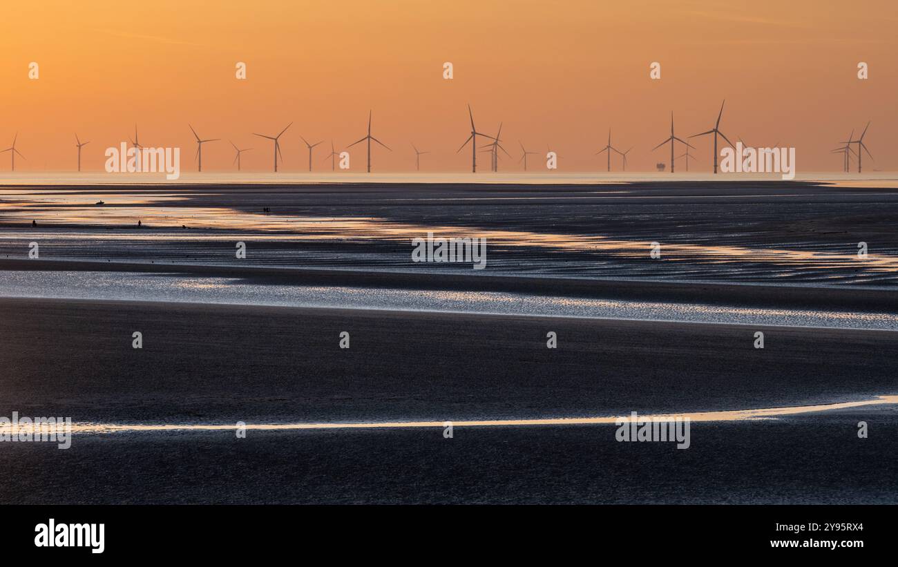 The sun sets behind wind turbines in the Irish Sea viewed from the ...