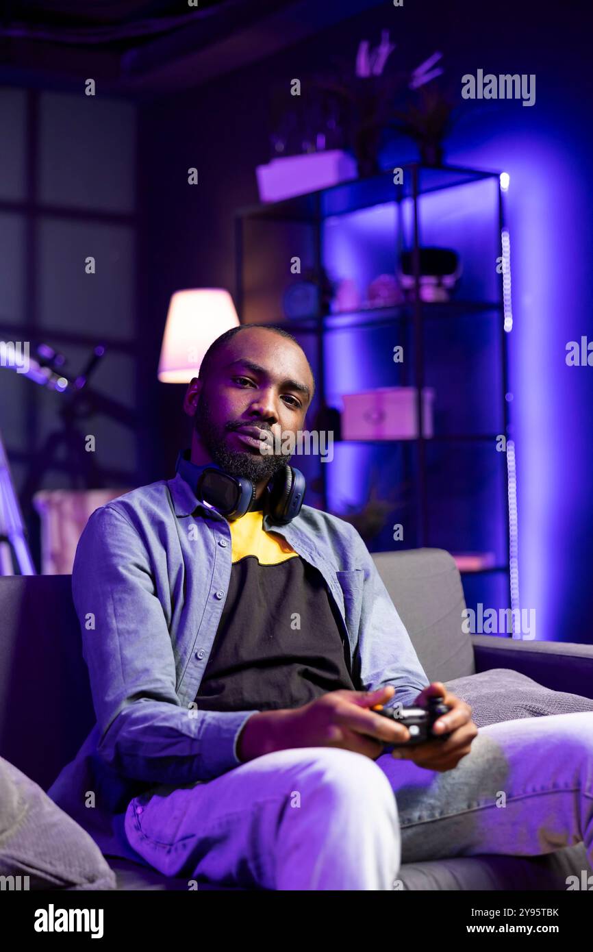 Portrait of player in RGB lit home gaming with joystick and enjoying ...