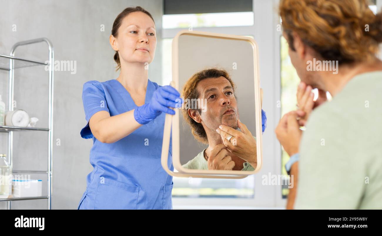 Man carefully examines his face with mirror after cosmetic surgery in ...