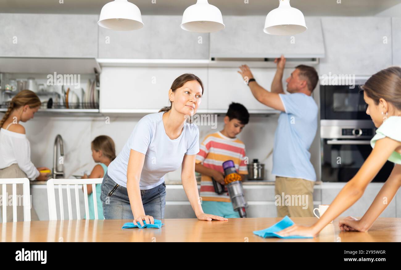 Daughters with mom wipe table, dad and brother do kitchen household ...