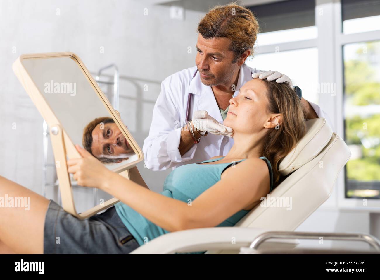 Adult male doctor examining face of female patient Stock Photo - Alamy