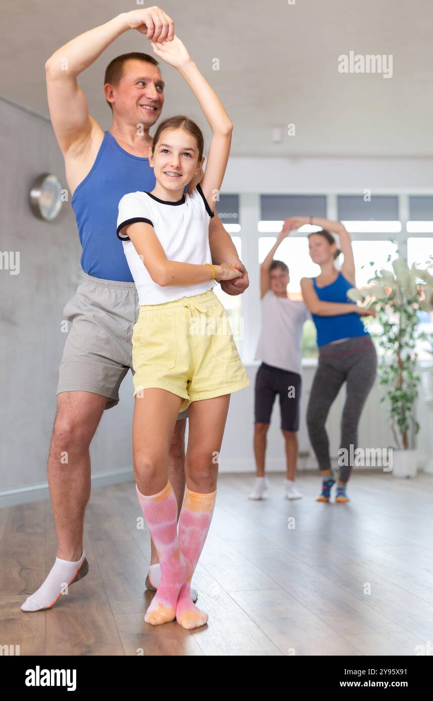 Happy father and daughter practicing dance in pairs together with other ...