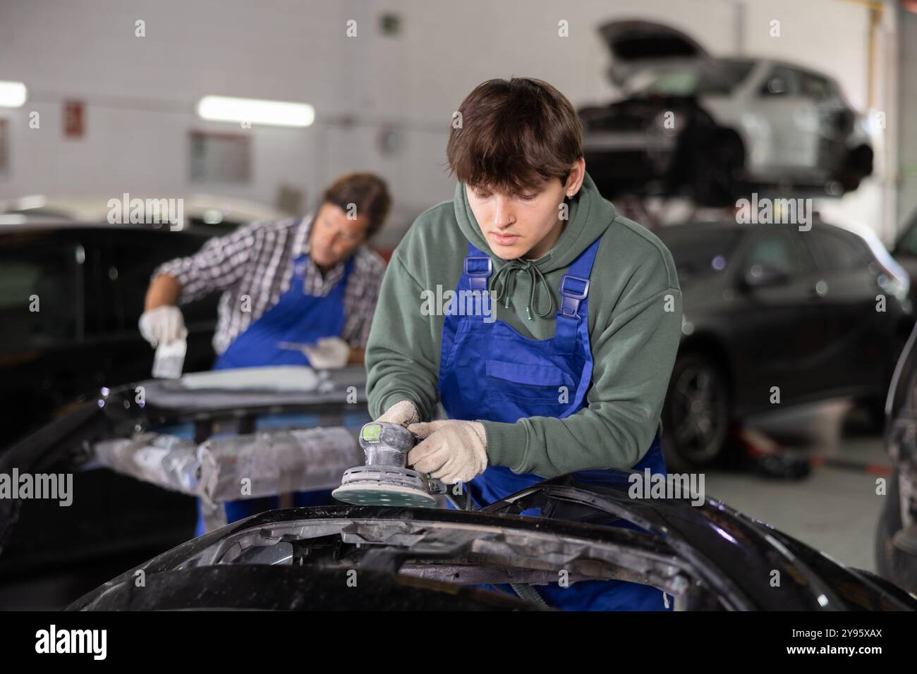 Young guy mechanic polishes car with machine Stock Photo - Alamy