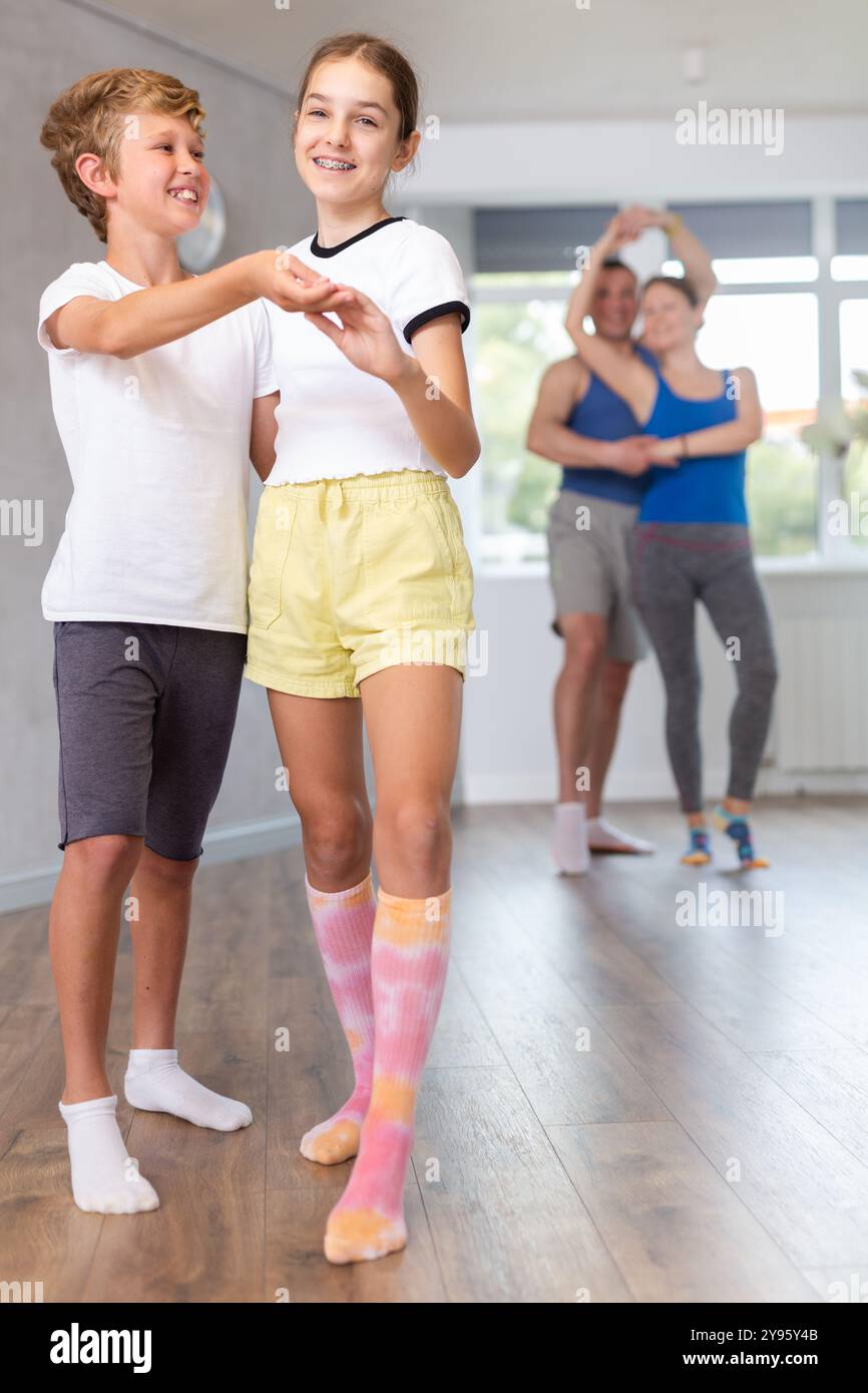 Positive preteen girl exercising dance moves with her brother during ...
