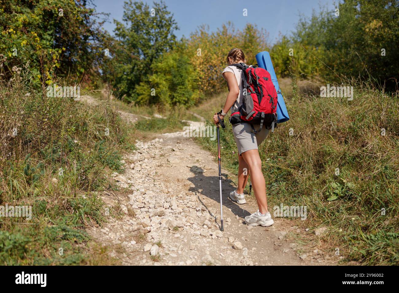 A hiker is ascending a rugged, rocky trail while enjoying the beauty of ...