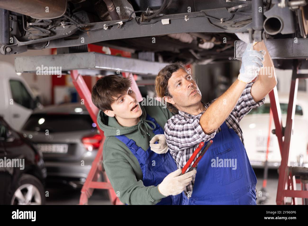 Guy and man mechanics repairing underbody of car Stock Photo - Alamy
