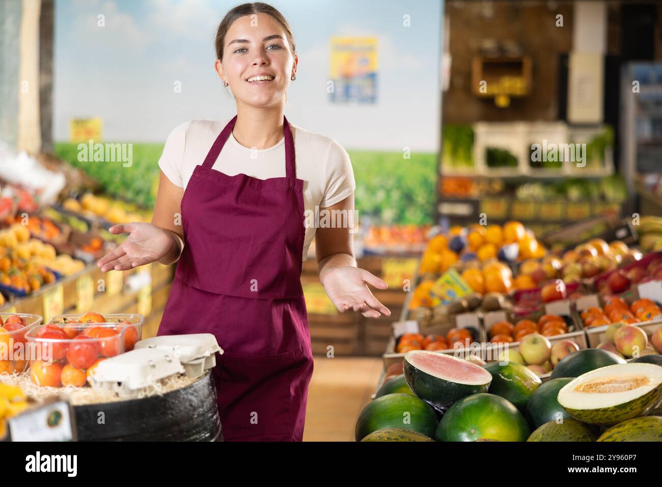 Positive and friendly store girl employee stands with arms crossed on chest and waits for ...