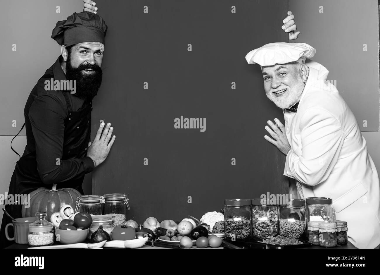 Chef cook showing at blank board. Two smiling male chefs, cooks or ...
