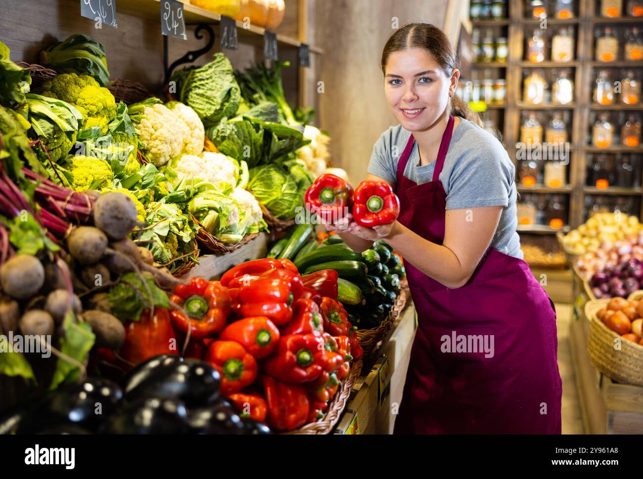 Female grocery store worker lays out bell peppers on the counter and ...