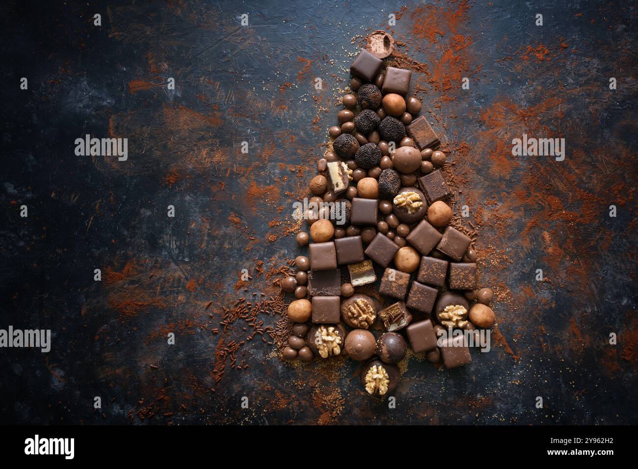 Chocolate and pralines laid in the shape of a Christmas tree on a dark ...