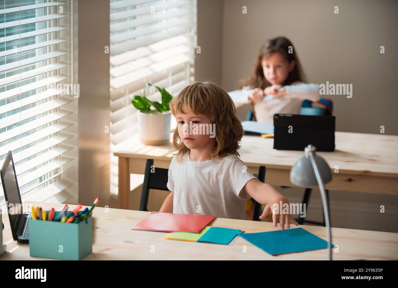 Cute pupil writing at desk in classroom at the elementary school ...