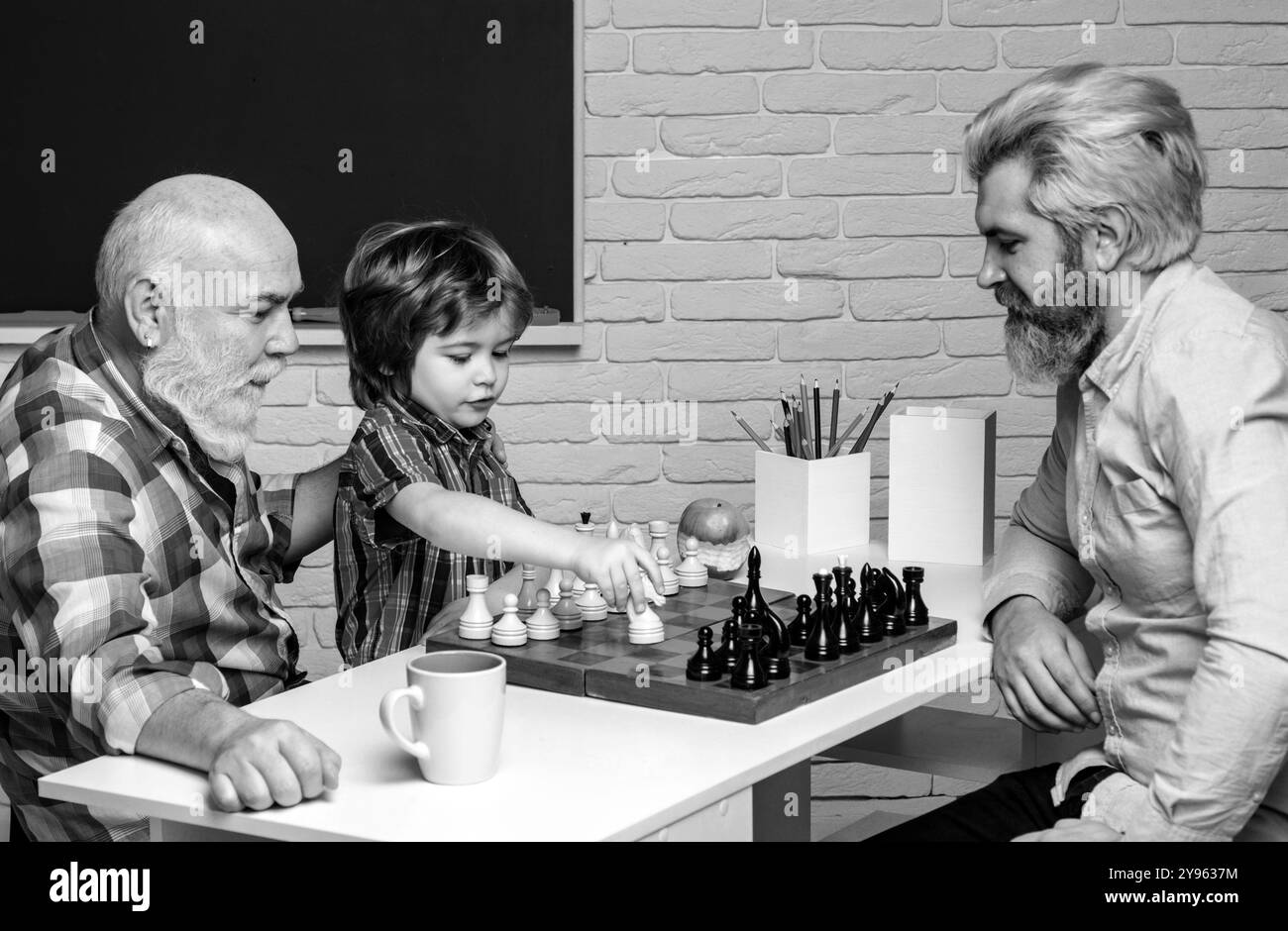 Grandfather father and son playing chess. Grandpa teaching grangson at ...