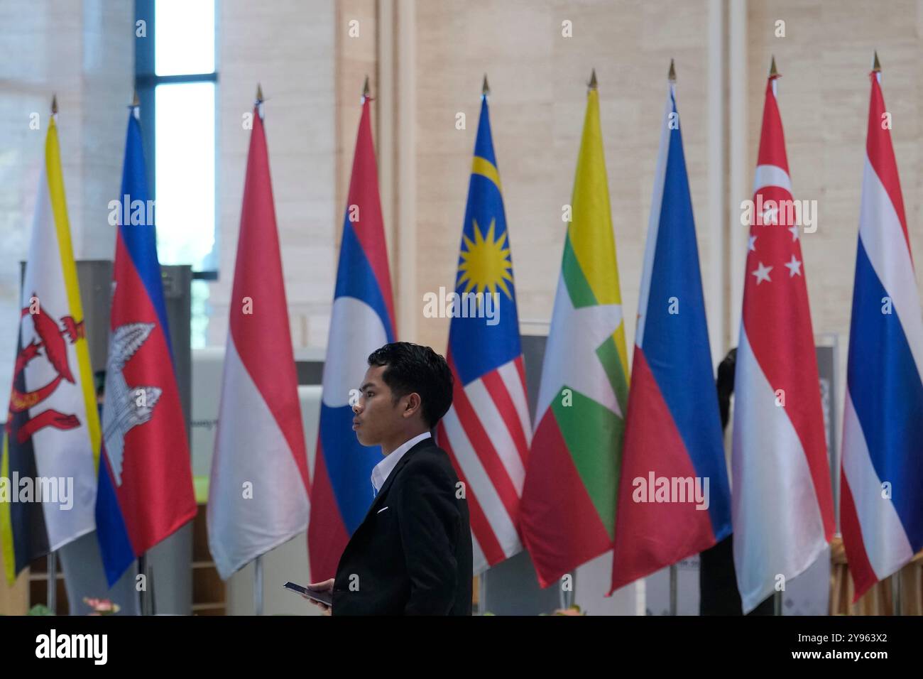 An officer walks in front of flags of nations participating in the ...