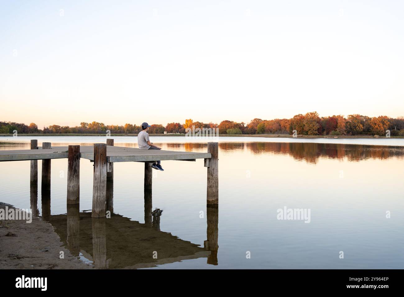 Boy Sitting on Dock in the Fall Stock Photo - Alamy