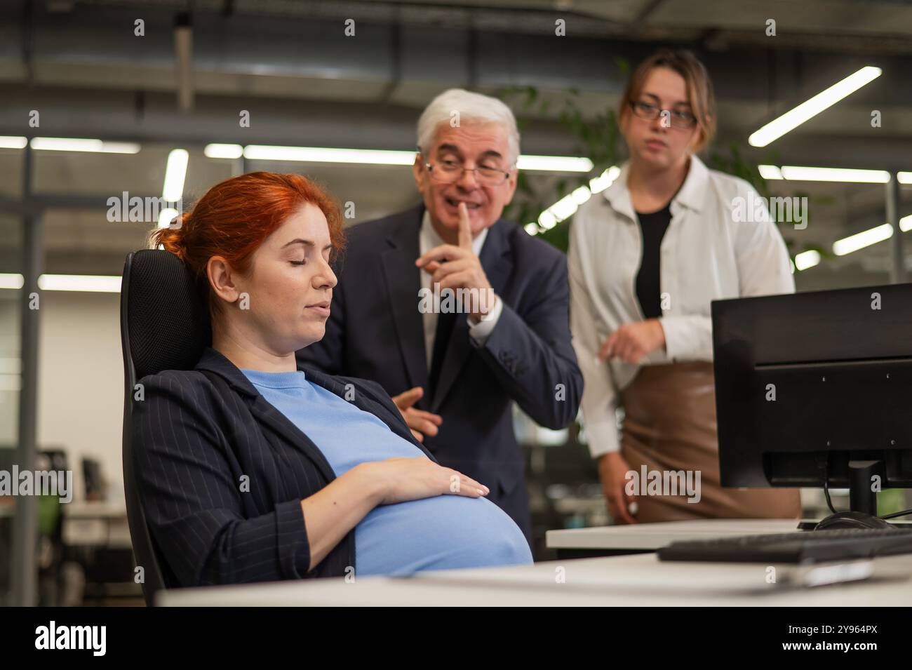 Elderly Caucasian man and woman giggling behind their sleeping pregnant ...
