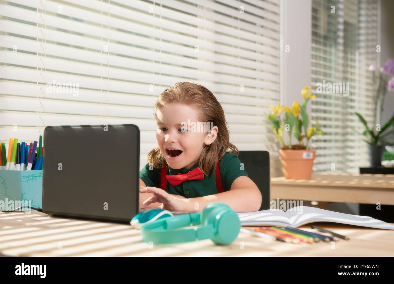 Child boy using a laptop and study online lesson. Pupil at school. Cute ...
