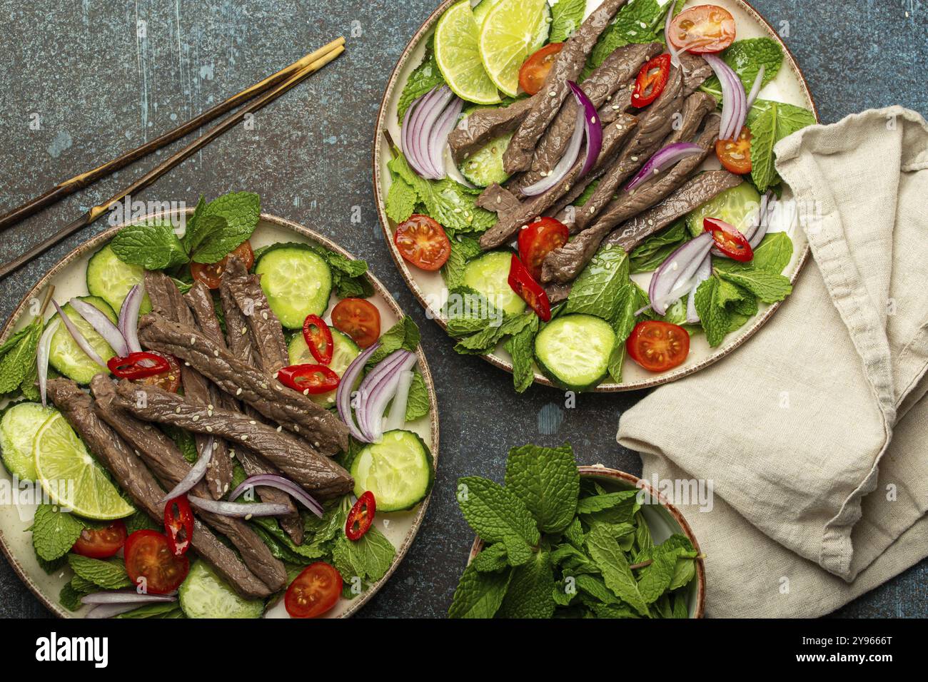 Two plates with traditional Thai beef salad with vegetables and mint ...