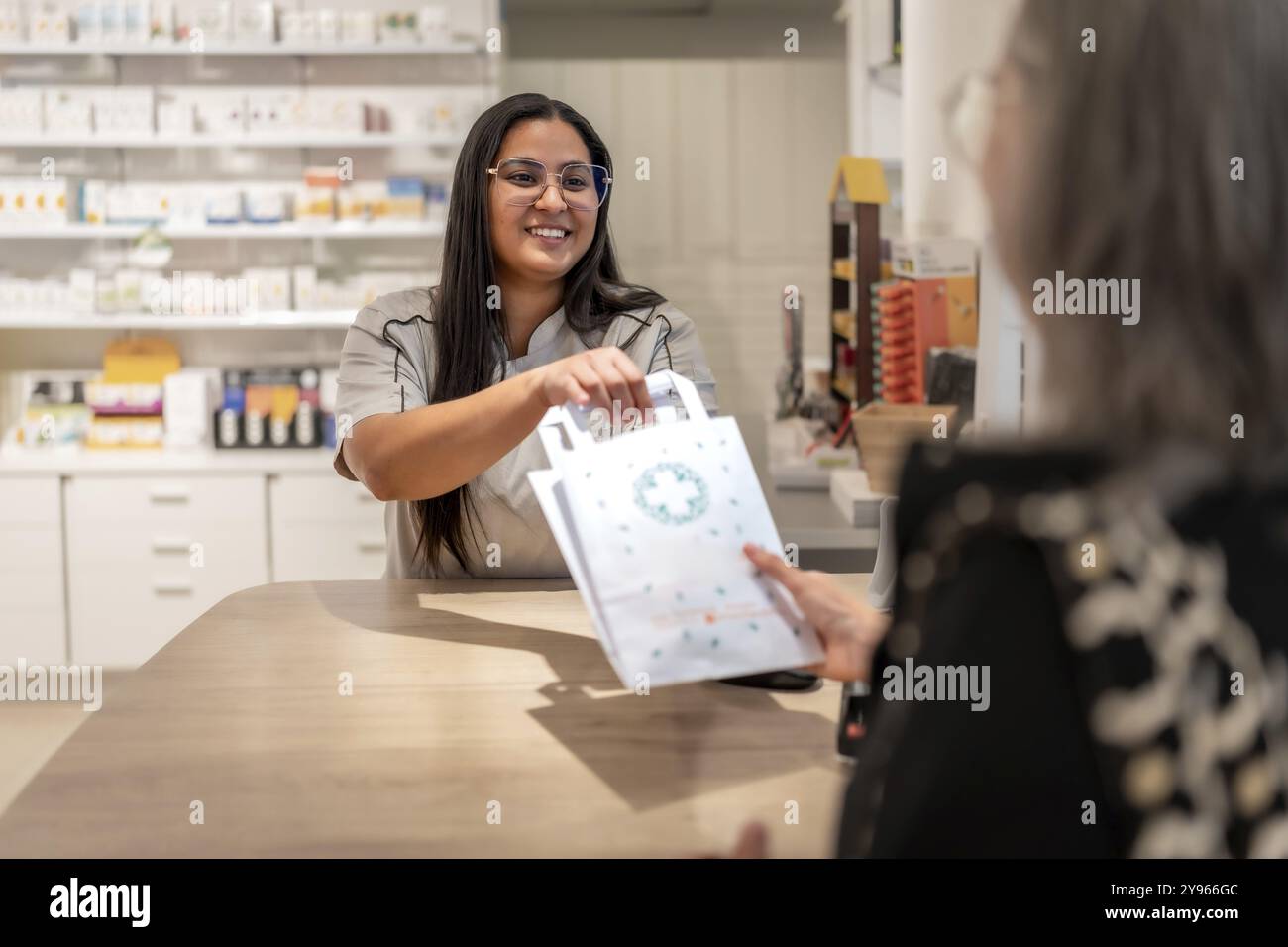 Pharmacist giving medicine into paper bag to a customer at the counter ...