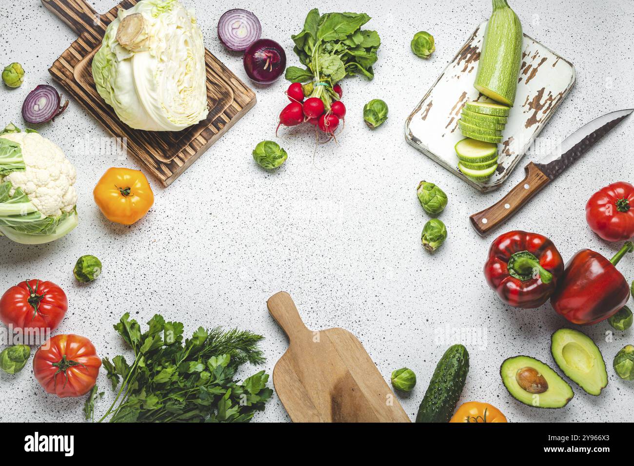 Fresh various vegetables with wooden cutting boards and knife on white kitchen table top view ...