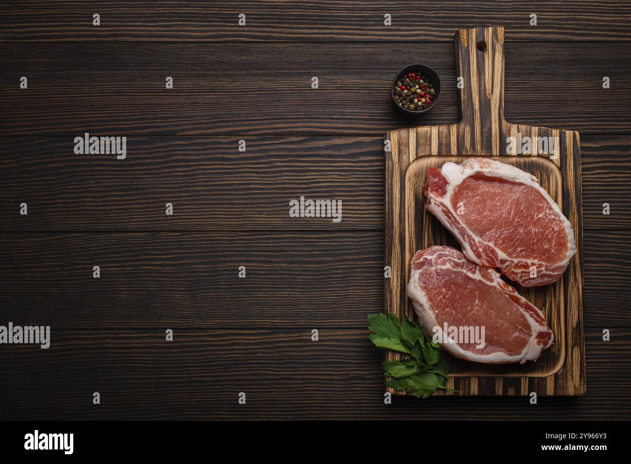 Cut raw meat pork steaks with seasonings on kitchen cutting board ...
