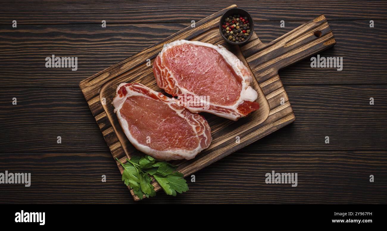 Cut raw meat pork steaks with seasonings on kitchen cutting board ...