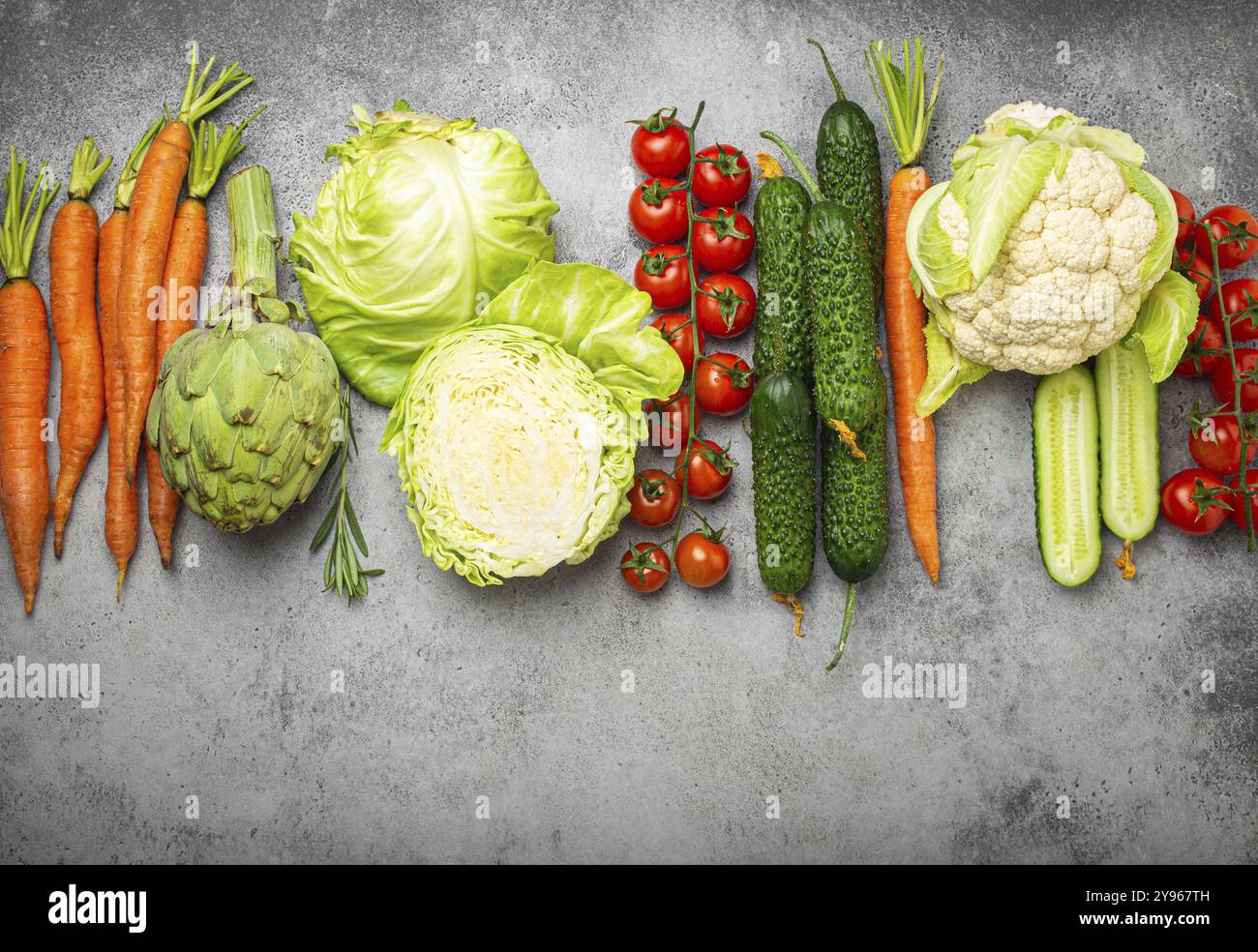 Fresh various organic vegetables arranged in line on rustic grey stone ...