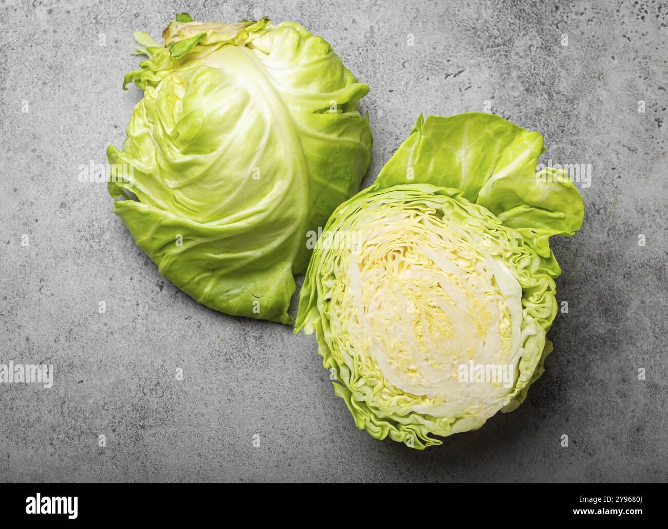 Fresh raw organic farm cabbage cut in half on grey rustic stone ...