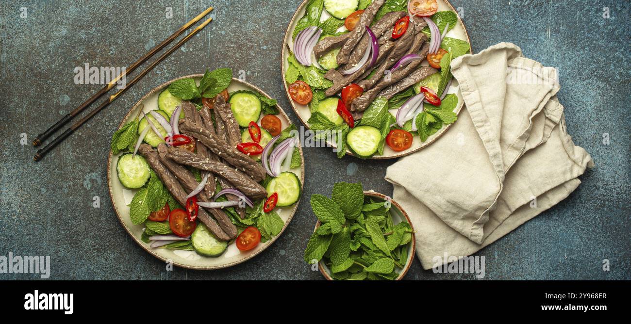 Two plates with traditional Thai beef salad with vegetables and mint ...