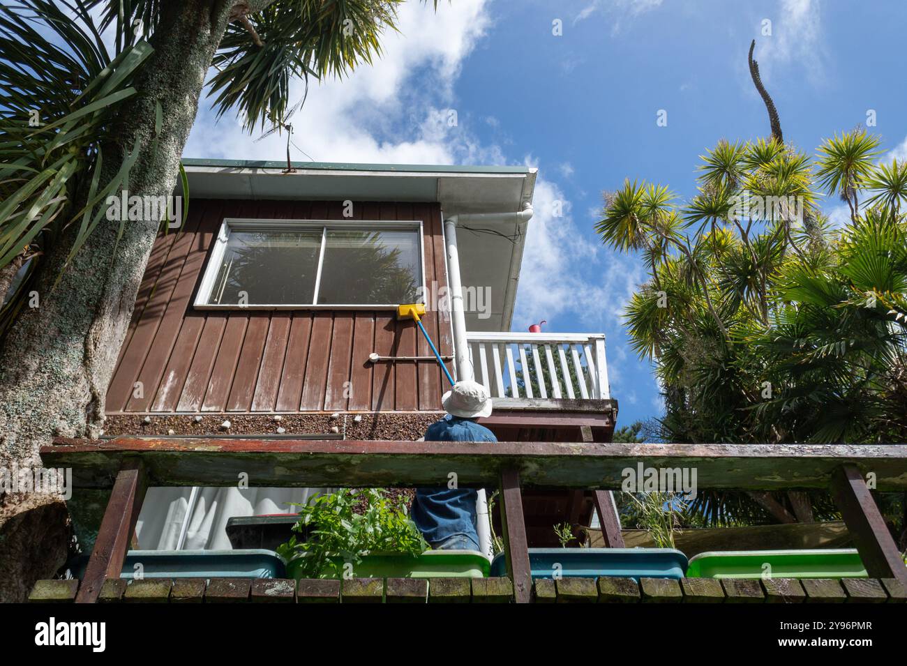 Man cleaning walls and windows using a long brush for a two storey ...