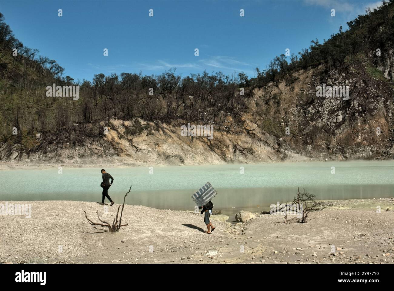 Men walking on sandy landscape on the crater of Mount Patuha, which is ...
