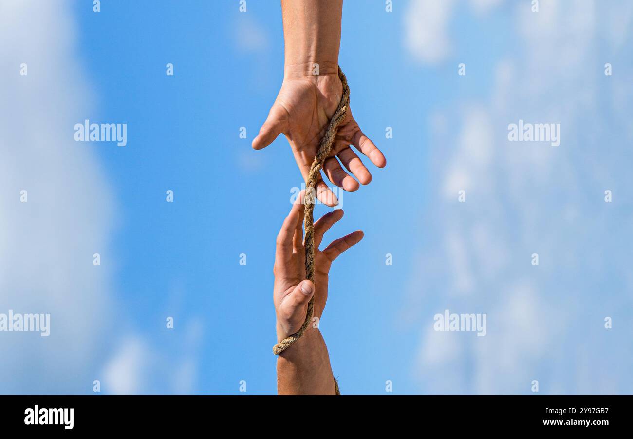 Hand holds the rope and helps the person escape.Two hands, helping hand of a friend. Rescue ...