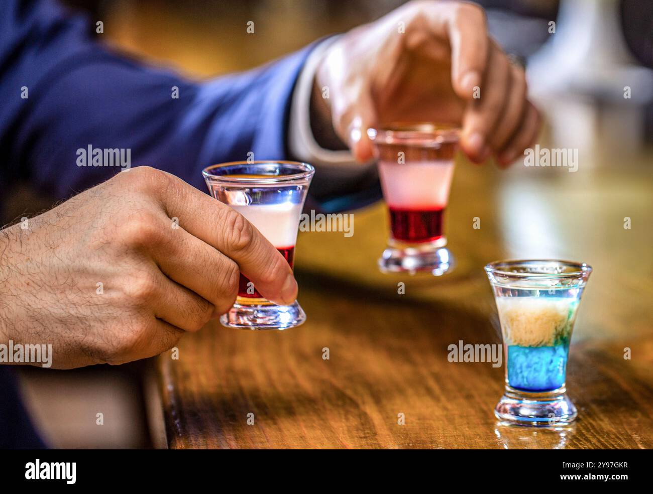 Male hands cheer with glasses of vodka and liqueur. Best friends ...