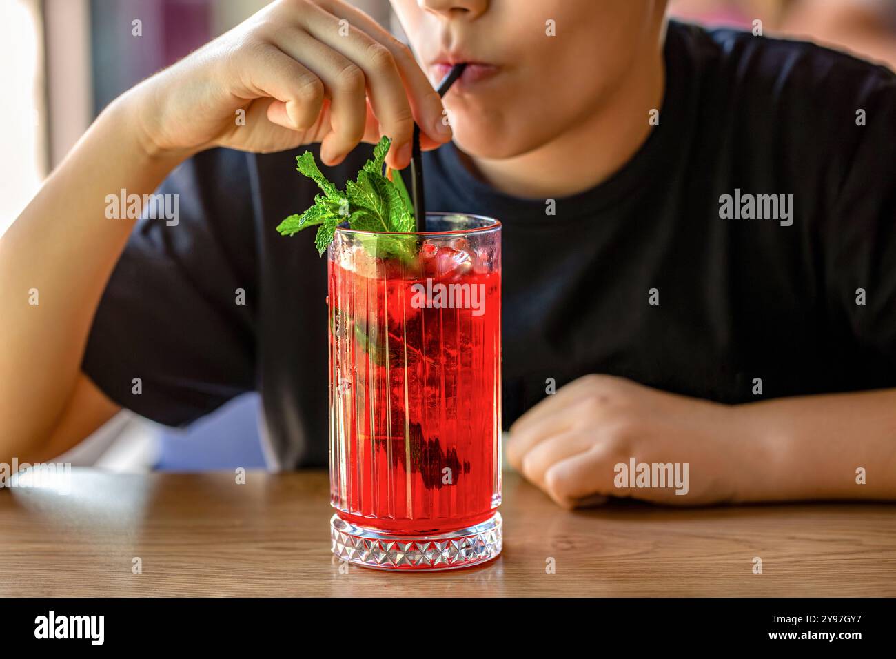 Child boy drinks strawberry cocktail, juice with mint. Kid hold the ...