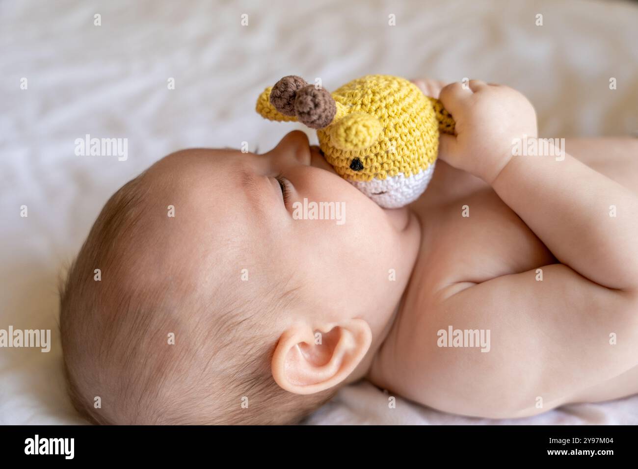 Newborn baby boy or girl with soft toy napping in bed Stock Photo - Alamy