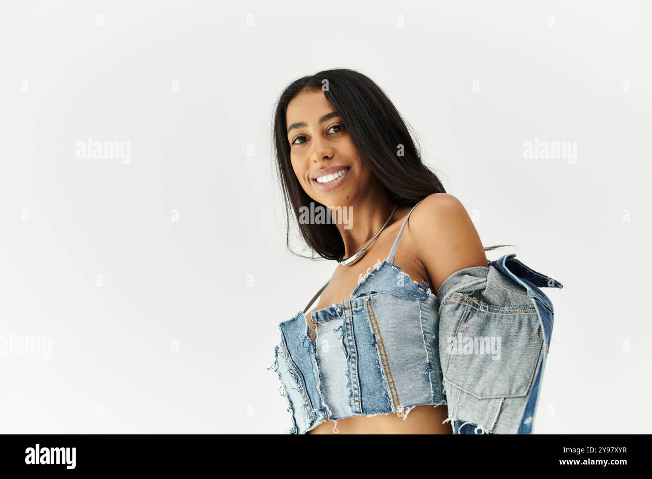 Radiating style and charm, a young woman poses in trendy denim, showcasing her unique flair ...