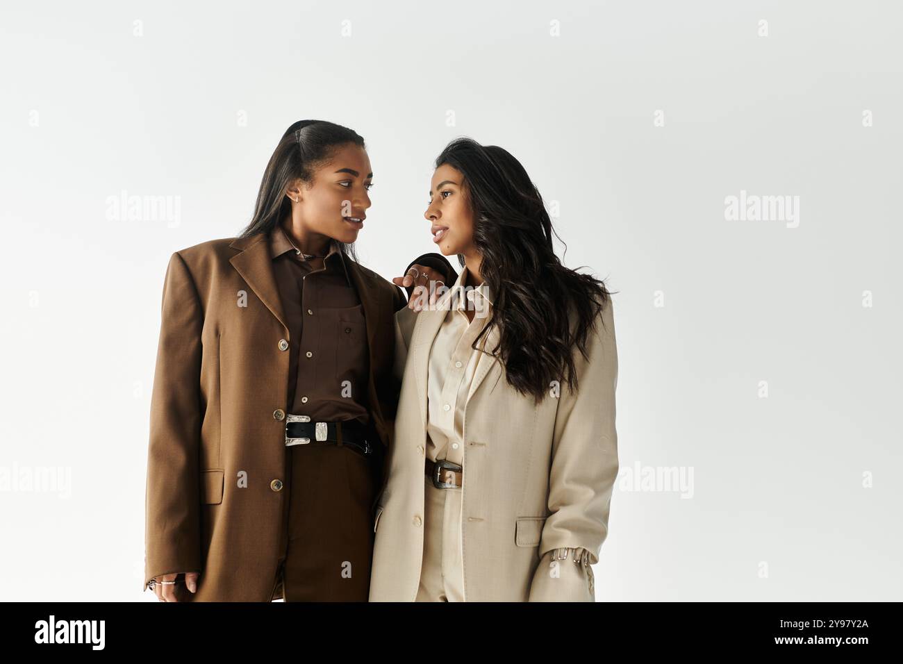 Two stylish young women chat animatedly, radiating confidence and ...
